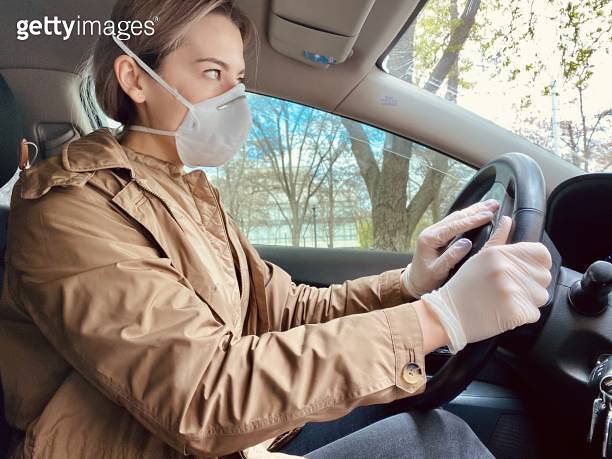 girl in a flu protective mask and gloves, against coronavirus, driving ...