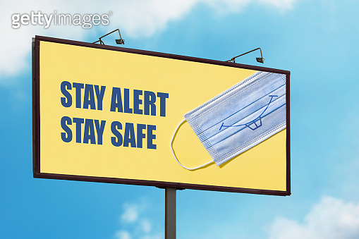 Stay Alert Stay Safe warning sign with smiling face mask on blue sky ...