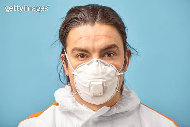A tired doctor in a respirator with traces of a mask on his face. An ...