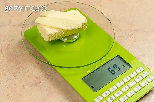 piece of the butter on a light green kitchen digital scale 이미지 ...