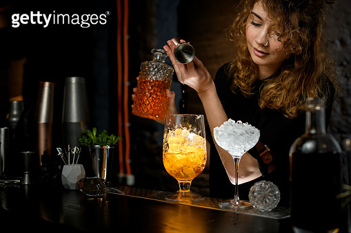 female bartender pours drink from jigger into mixing cup with ice. 이미지 (1222064847) - 게티이미지뱅크