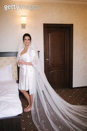 Morning of beautiful bride. Woman in white negligee in hotel. Back view ...