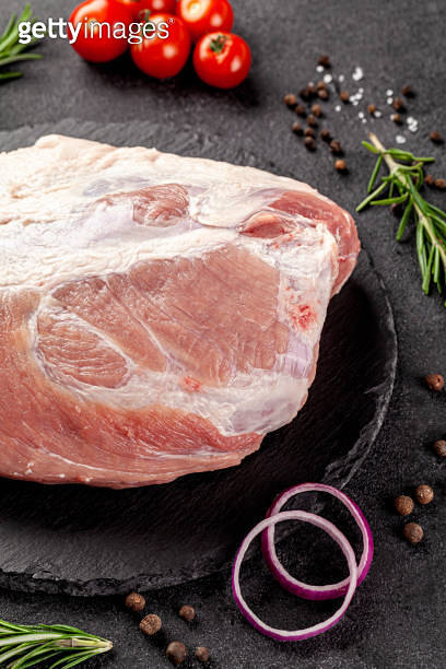 A large piece meat of raw pork, hip or tenderloin on a black background ...