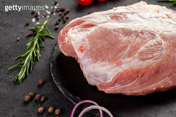 A large piece meat of raw pork, hip or tenderloin on a black background ...