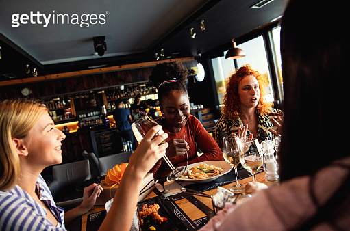 Group of young female friends having fun in restaurant, talking and ...