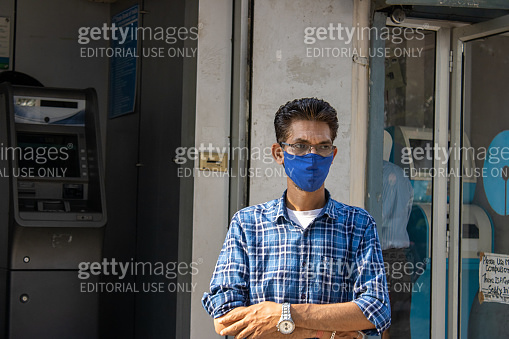 A customer outside the bank wears a face mask as a precaution for the ...