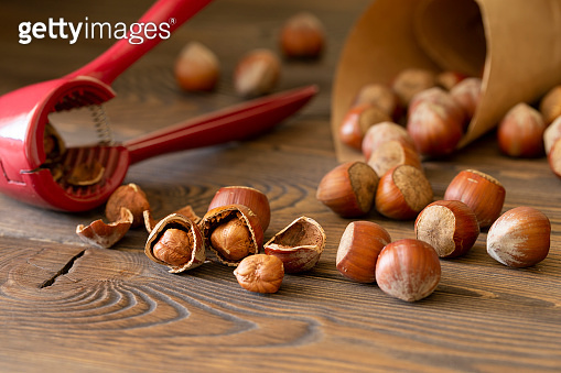 Hazelnuts with a red nutcracker in a bowl on a wooden board, nutshell ...