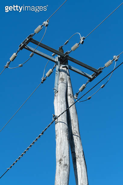 Old wooden three-phase electric utility pole with clear blue sky in ...