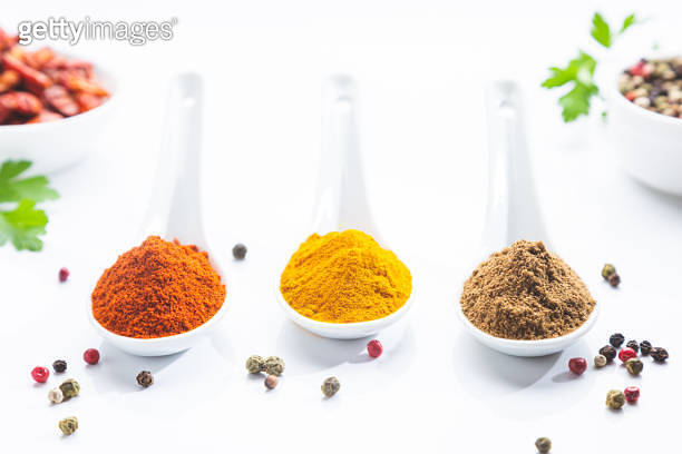 Three white spoons with paprika, turmeric and cumin on a white ...