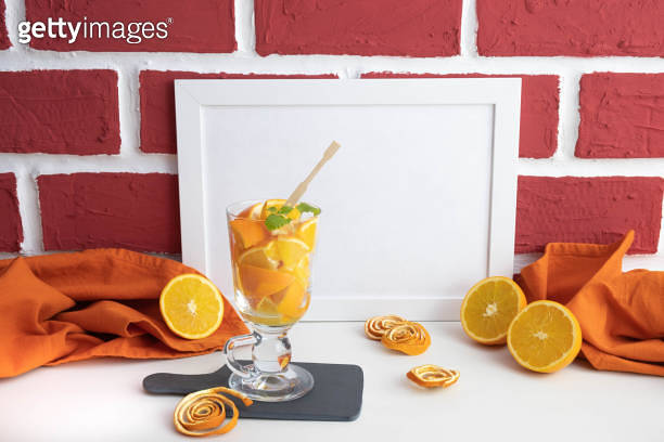 juice glass full of orange slices, back white photo frame, back brick ...