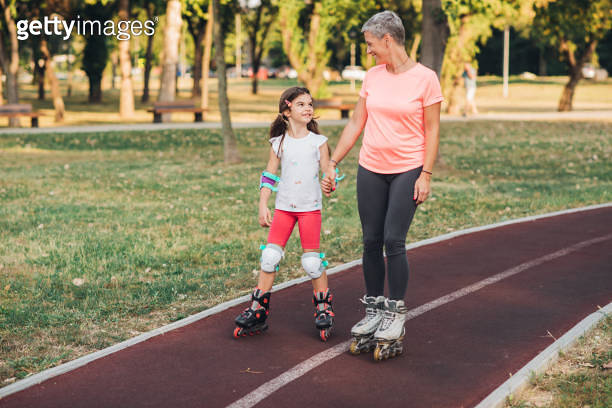 Little girl learning from her mom how to ride rollerblades 이미지 ...