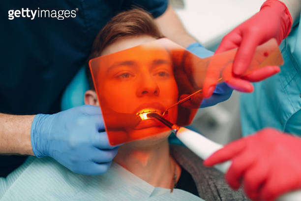 Dentistry. Dentist and patient. Light curing seal. UV dental lamp and ...