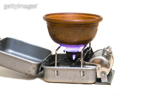 Tourist primus with a burning fire on which is a plate. Cooking food in ...