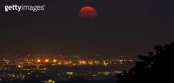 A dark red harvest moon rise over a city (1278330526) - 게티이미지뱅크
