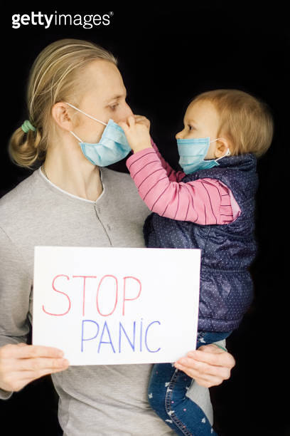 Father (man) and daughter (child) with anti panic poster "stop panic", wearing medical masks on ...