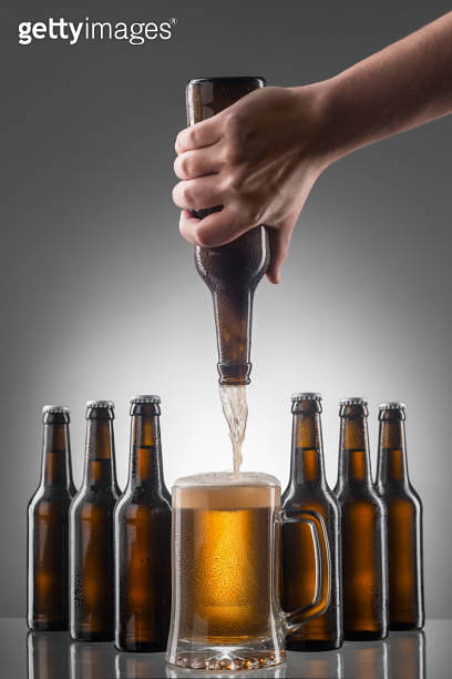 Bartender pouring beer into glassy mug. Six misted brown bottles 이미지 ...
