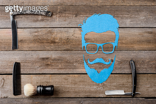 Comb, a man face silhouette, straight razors and a brush on the wood ...