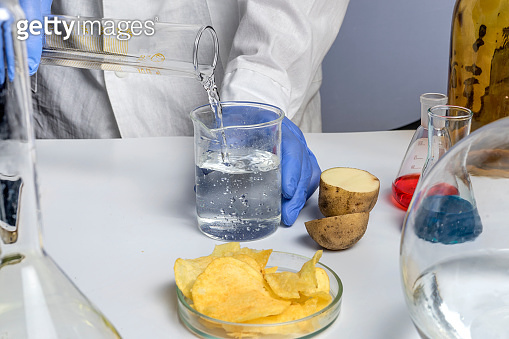 Food safety expert holding test tubes in hands checking potato chips in ...