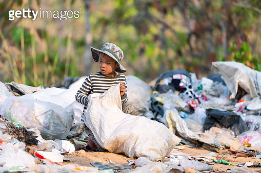 A poor boy collecting garbage waste from a landfill site in the ...
