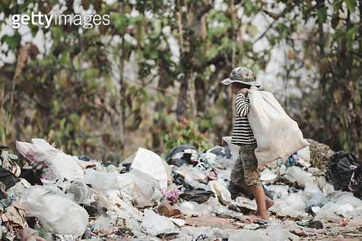 A poor boy collecting garbage waste from a landfill site. Concept of ...