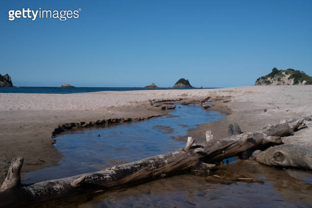 Hahei beach white sand and blue sea with small stream through sand 이미지 ...