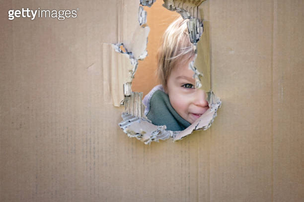 Sweet toddler child, cute blond boy, hiding in cardboard box, looking ...
