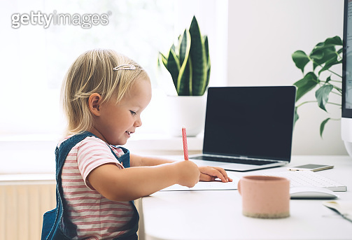 Little girl studying and drawing at desk. Preschool child using ...