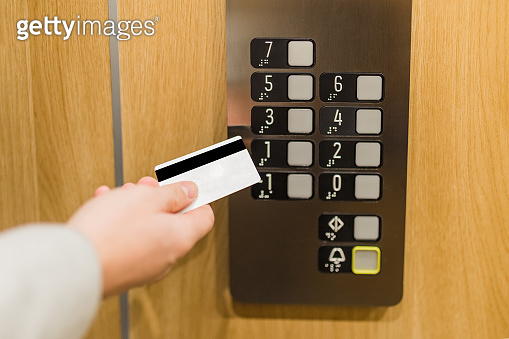 Close up of man holding cardkey on control panel elevator access ...