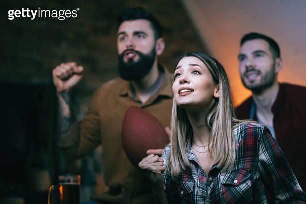 Young woman and her friends watching rugby match on TV at home. 이미지 ...