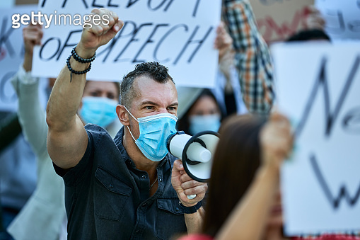 Angry activist with raised fist shouting through megaphone on ...