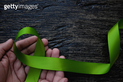 Top view of hands holding lime green color ribbon on dark background ...