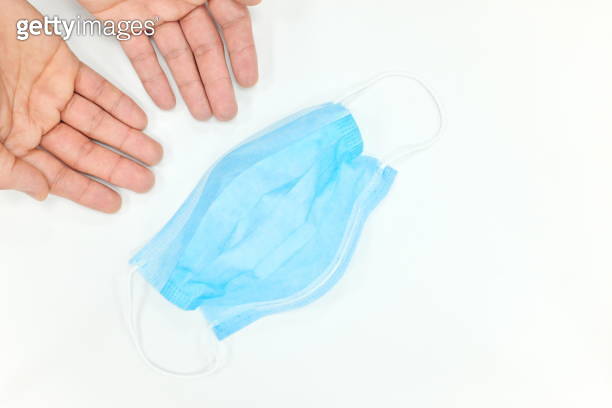 Hand laying down a face mask on the table. Coronavirus covid-19 ...