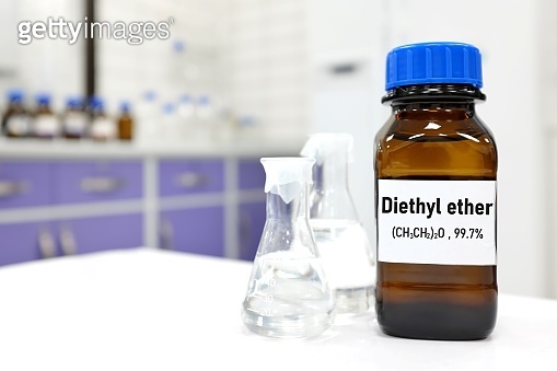 Selective focus of diethyl ether liquid chemical compound in dark glass ...