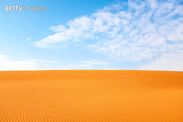 Bright orange color rippled desert sand and clear blue sky for a hot ...