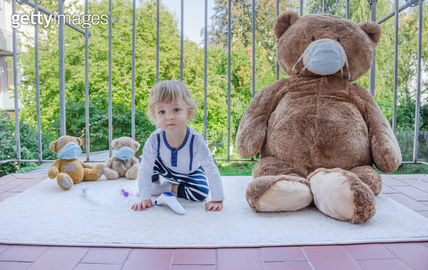 Child in home quarantine playing in the balcony with his sick teddy ...