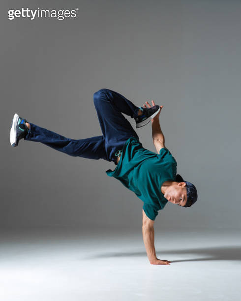 Cool b-boy dancing breakdance on the floor in studio isolated on gray ...