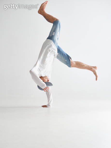 Young breakdancer stands on one hand upside down dancing hip-hop ...