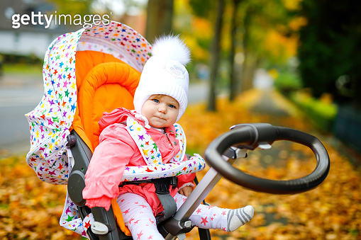 Cute little beautiful baby girl sitting in the pram or stroller on ...