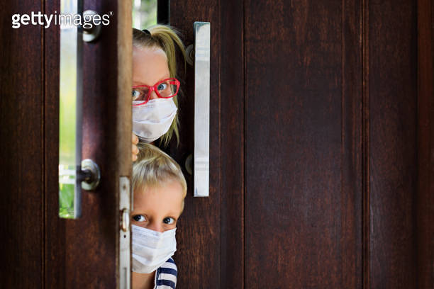 Kids wearing face masks peeking out the door 이미지 (1221621829) - 게티이미지뱅크
