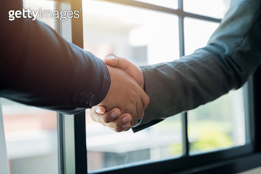 Two businessmen shaking hands agree to do business together to create a ...