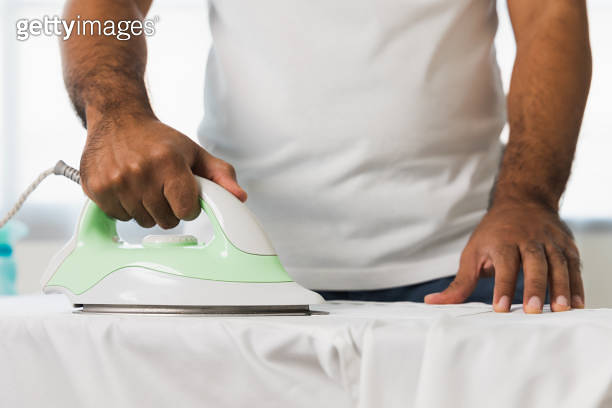 A man's hand using an iron. Iron the garment to make it smooth ...