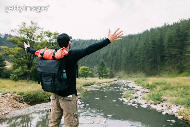 Young male nature explorer enjoying the view of the river in wilderness ...