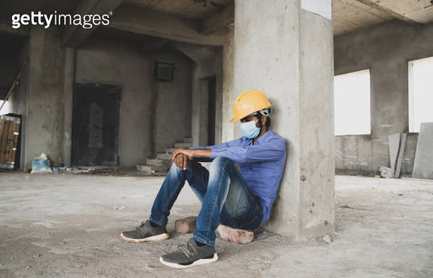 construction worker sitting sad and lonely at job site wearing a ...