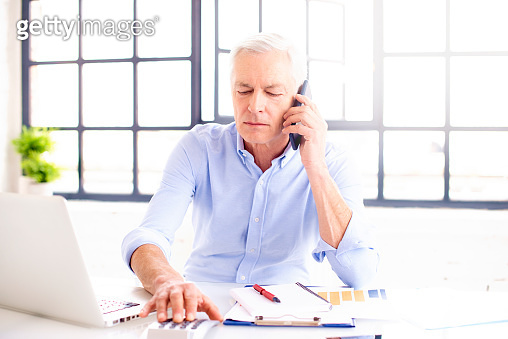 Shot of senior man sitting behind his laptop and talking with somebody ...