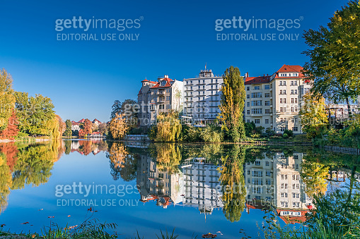 Park at the shore of Lake Lietzen with buildings reflecting in the ...