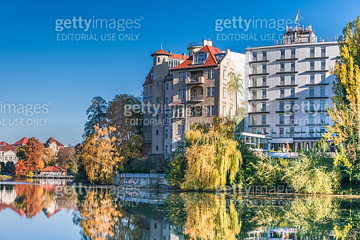 Park at the shore of Lake Lietzen with buildings reflecting in the ...