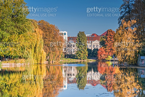 Facades and colorful trees reflecting in the water of Lake Lietzen in ...