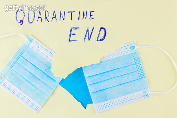 Quarantine end. Two parts of cut surgical mask on a yellow background ...