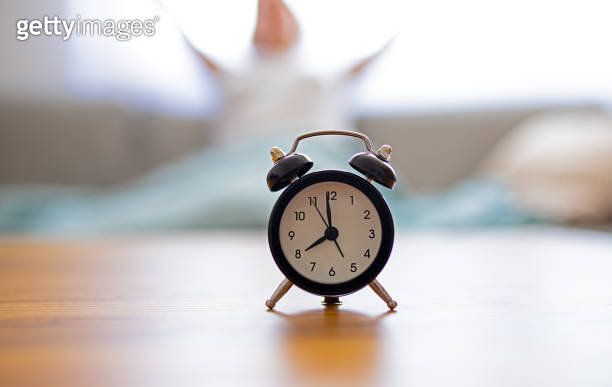 Woman waking up peacefully in her bed. Clock in front of waking up ...