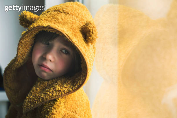 Sad child in isolation at home. Looking through the window. Covid-19 ...
